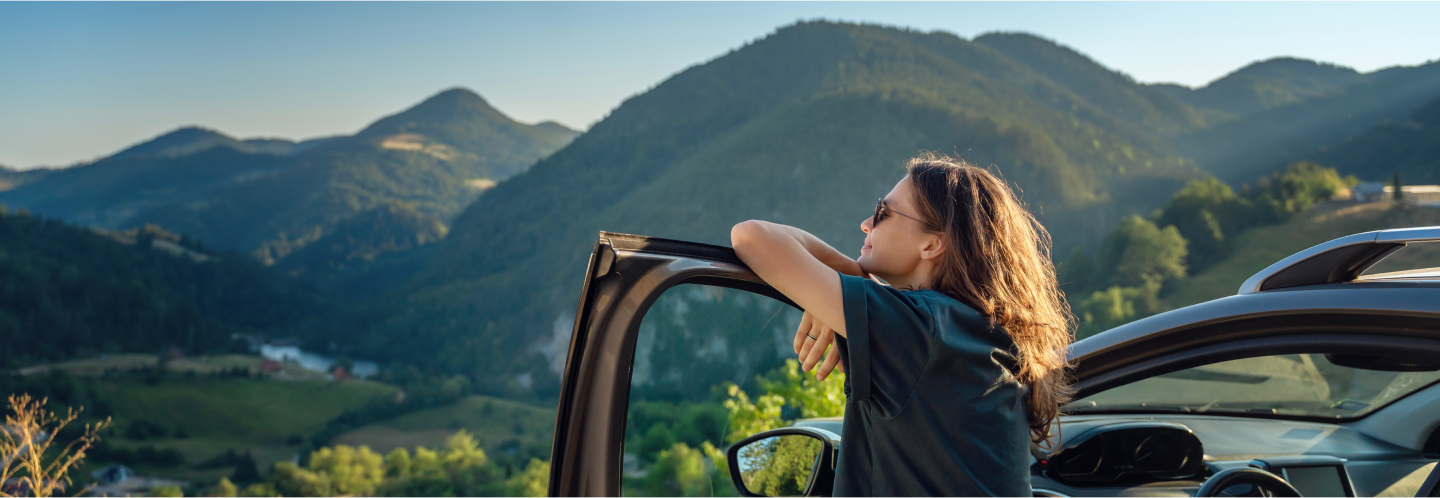 Image of a person looking blissfully at mountains | Raisin