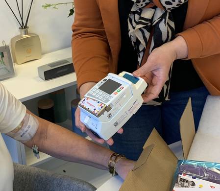 Zorgprofessional die infuuspomp laat zien aan TPV patiënt